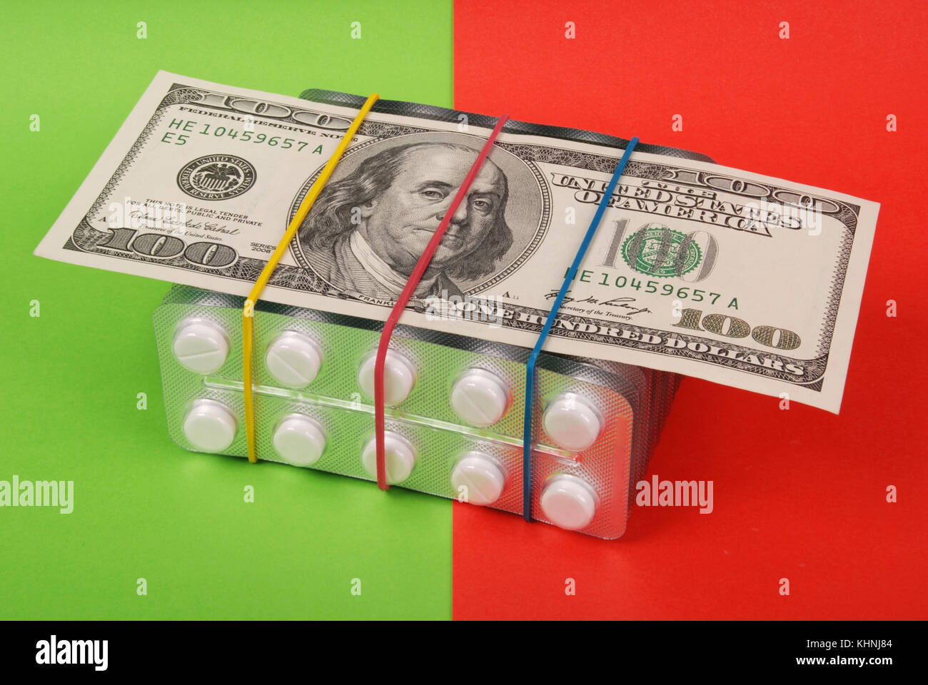 Hundred dollars lays on packing of white tablets. Red and green ...