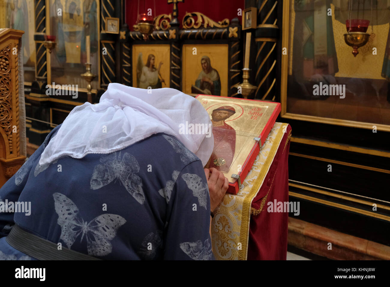 A Russian Orthodox pilgrim kissing a religious icon at the Church of ...