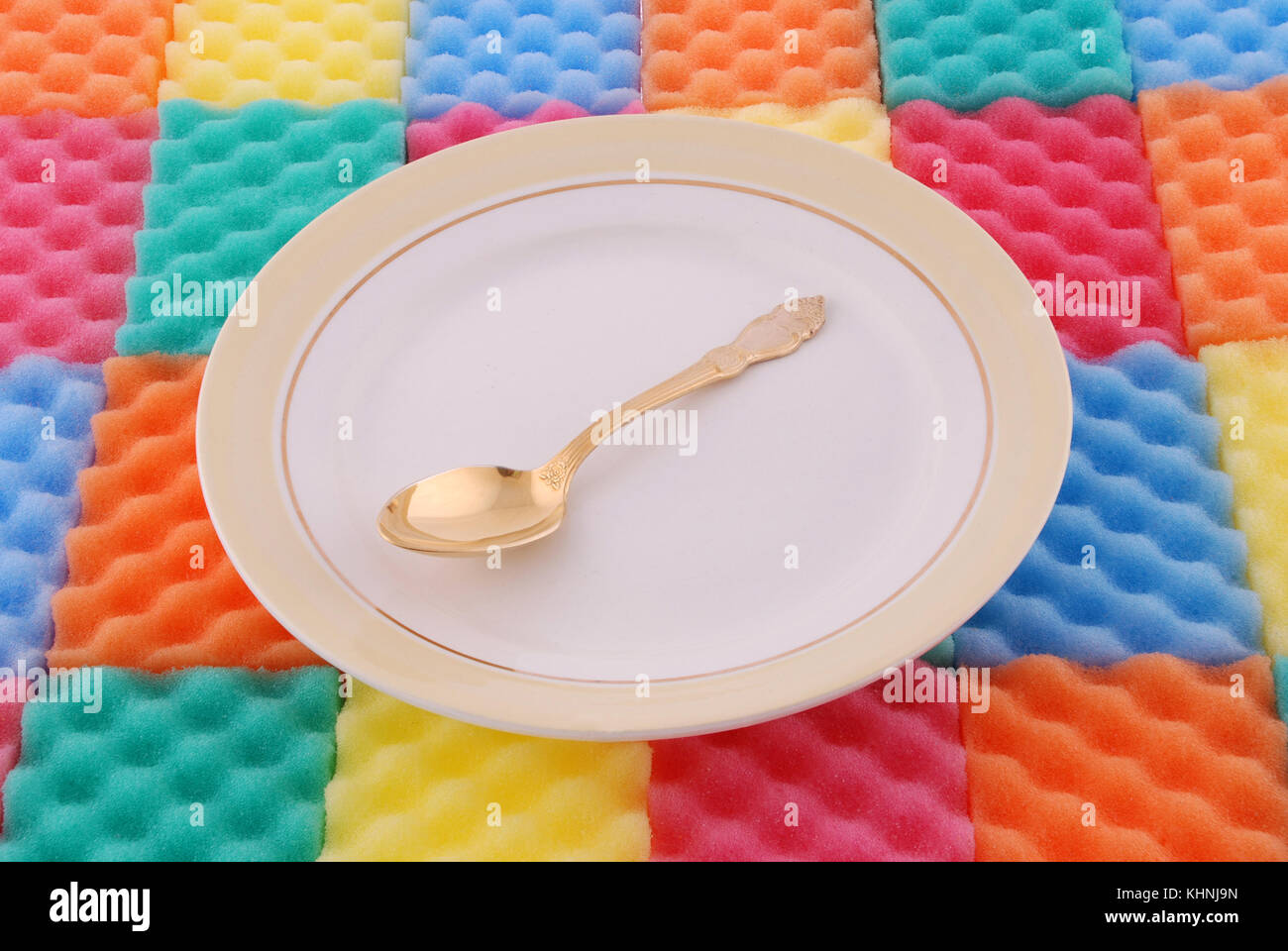 Plate with the gold spoon on a background color sponges Stock Photo - Alamy