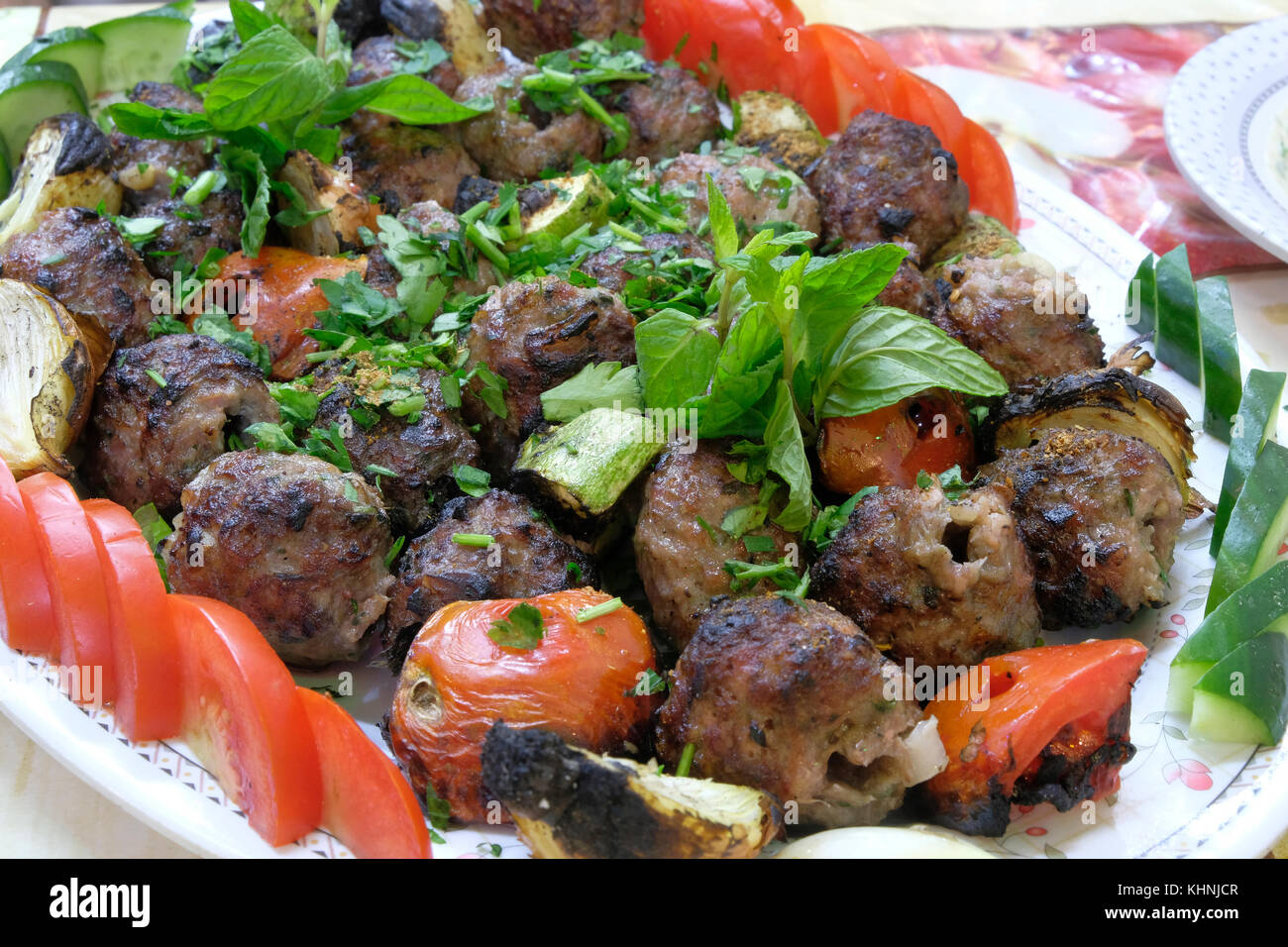 A dish of barbequed Kebabs or kabobs meat served with tomatoes and ...