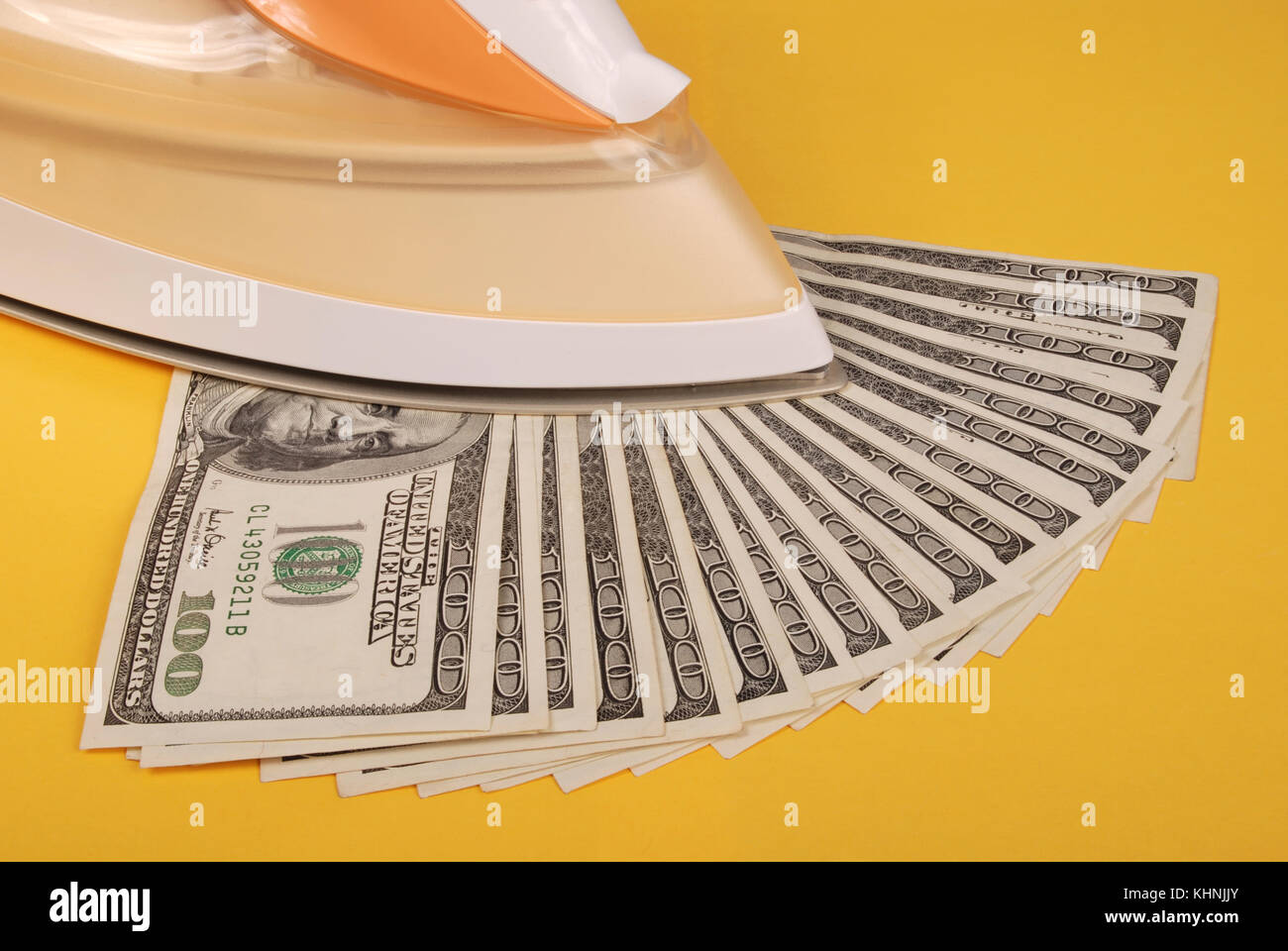 Dollars lay under an electric iron. On yellow background Stock Photo ...