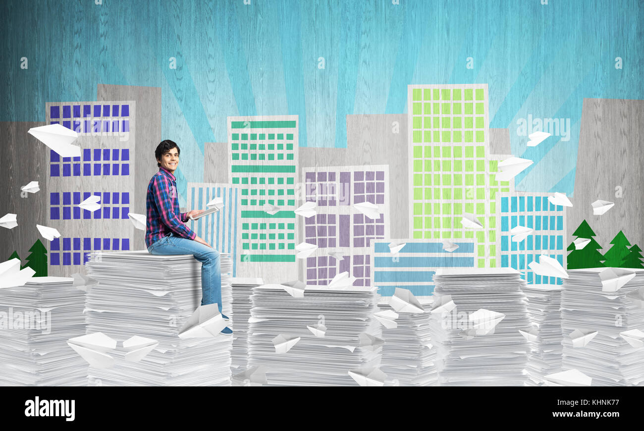 Young man sitting on pile of paper documents Stock Photo - Alamy