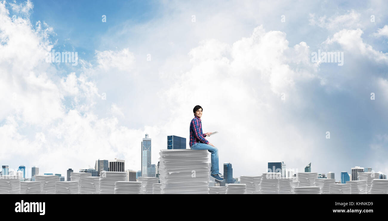 Attractive man sitting on pile of paper documents Stock Photo - Alamy