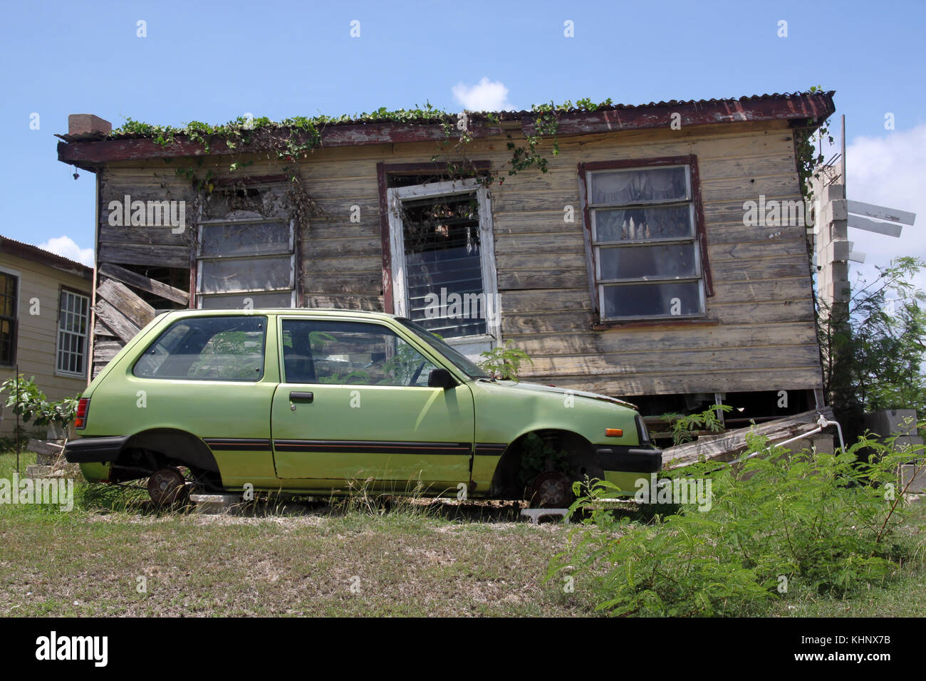 Old rusty house and green car withput wheels Stock Photo - Alamy