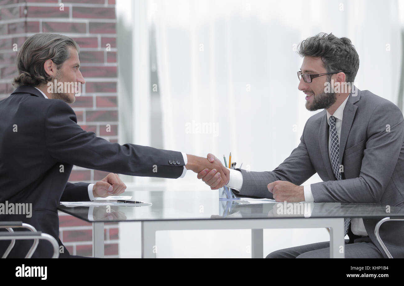 handshake of business partners sitting at their Desk Stock Photo - Alamy