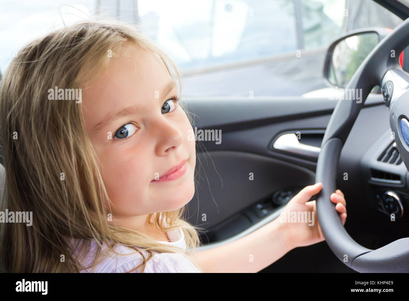Cute girl driving car with blond long hair Stock Photo - Alamy
