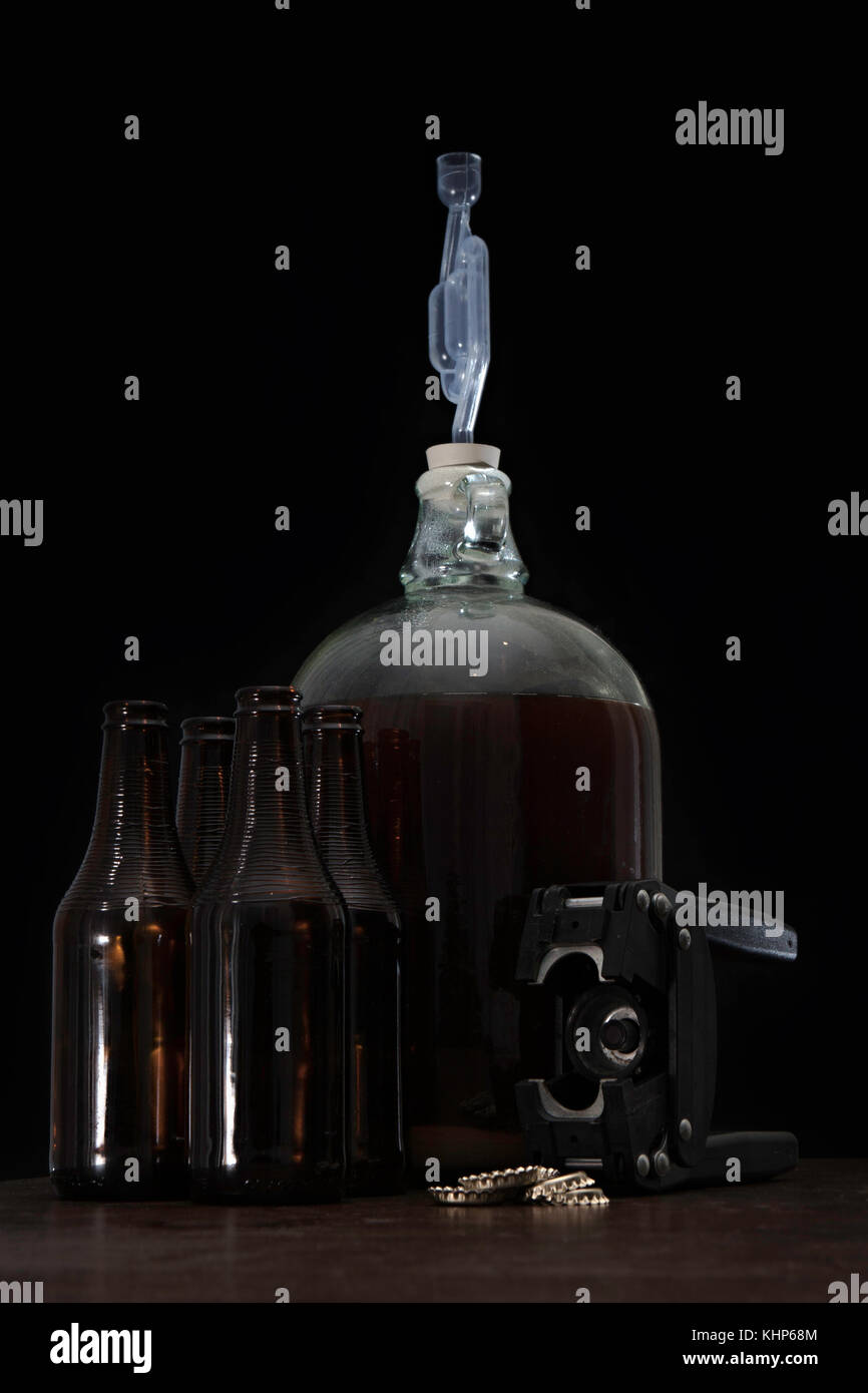 Fermented beer in a demijohn with airlock and hand capper with dark ...