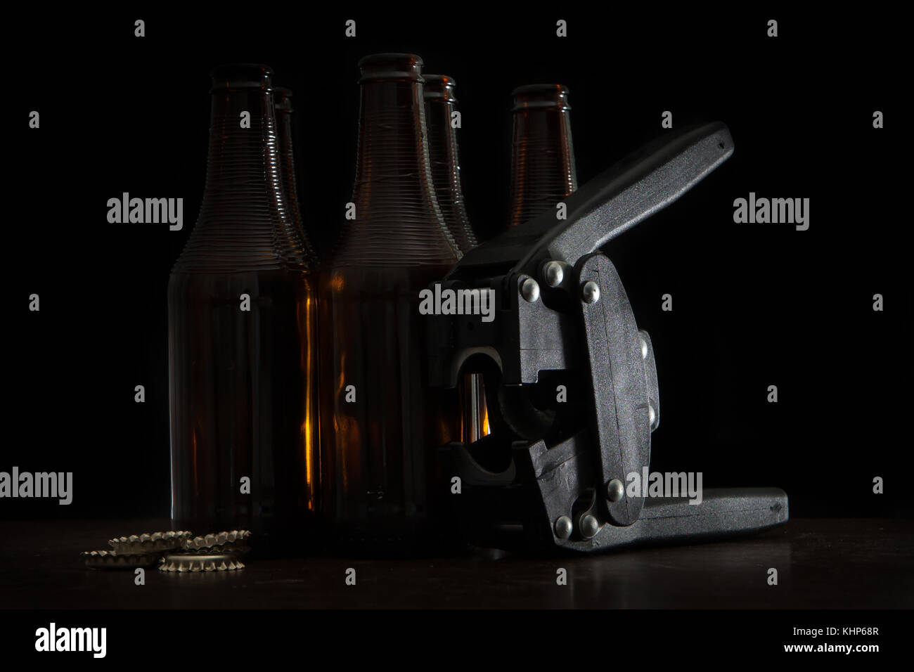 Full length of hand capper with five dark brown bottles and caps and ...