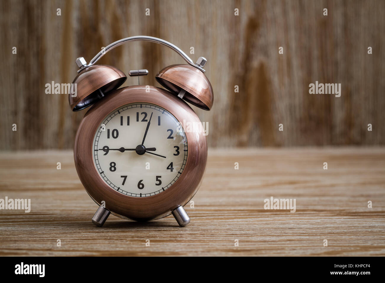 Old fashioned copper alarm clock on brown wooden background Stock Photo ...