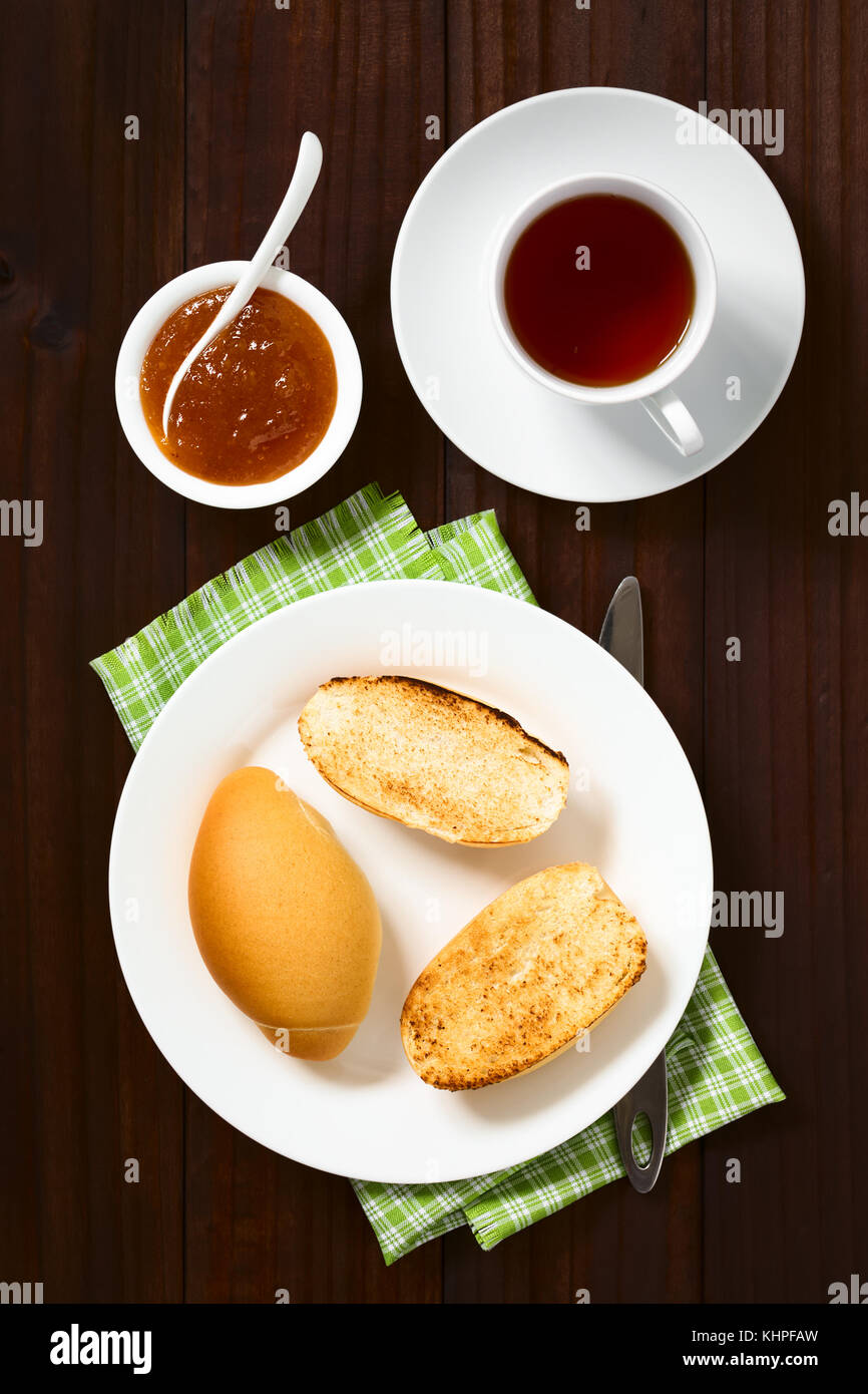 Toasted bread rolls with peach jam in bowl and tea on the side ...