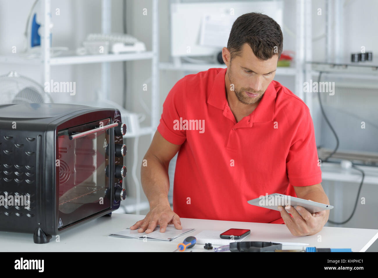 male technician checking his tablet to repair oven in kitchen Stock ...