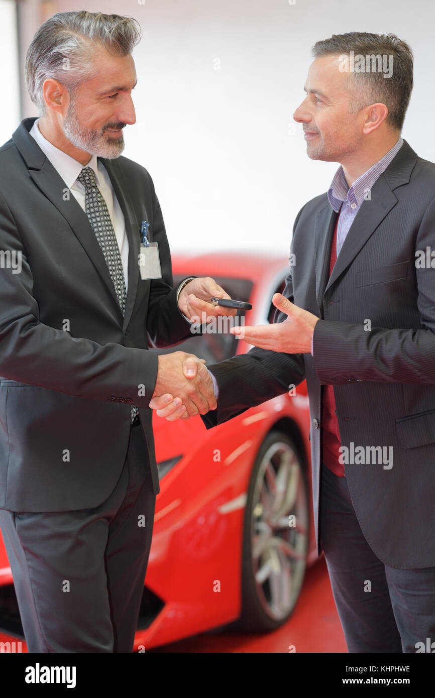 Car salesman shaking hands with customer and passing keys Stock Photo ...