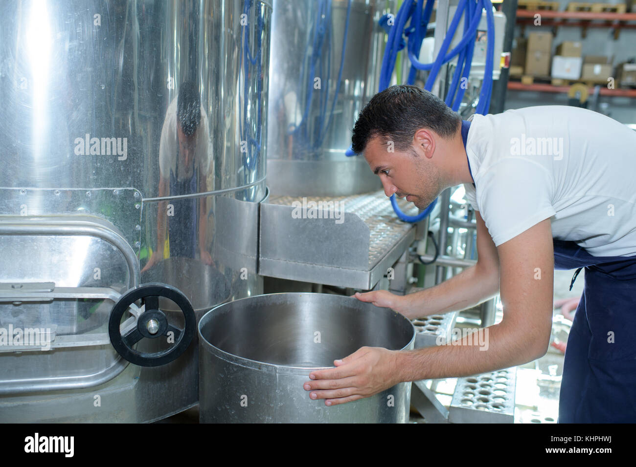 man putting a bucket under a big container Stock Photo - Alamy