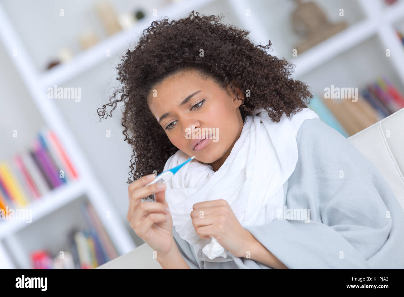 Woman wrapped up warm taking her temperature Stock Photo - Alamy