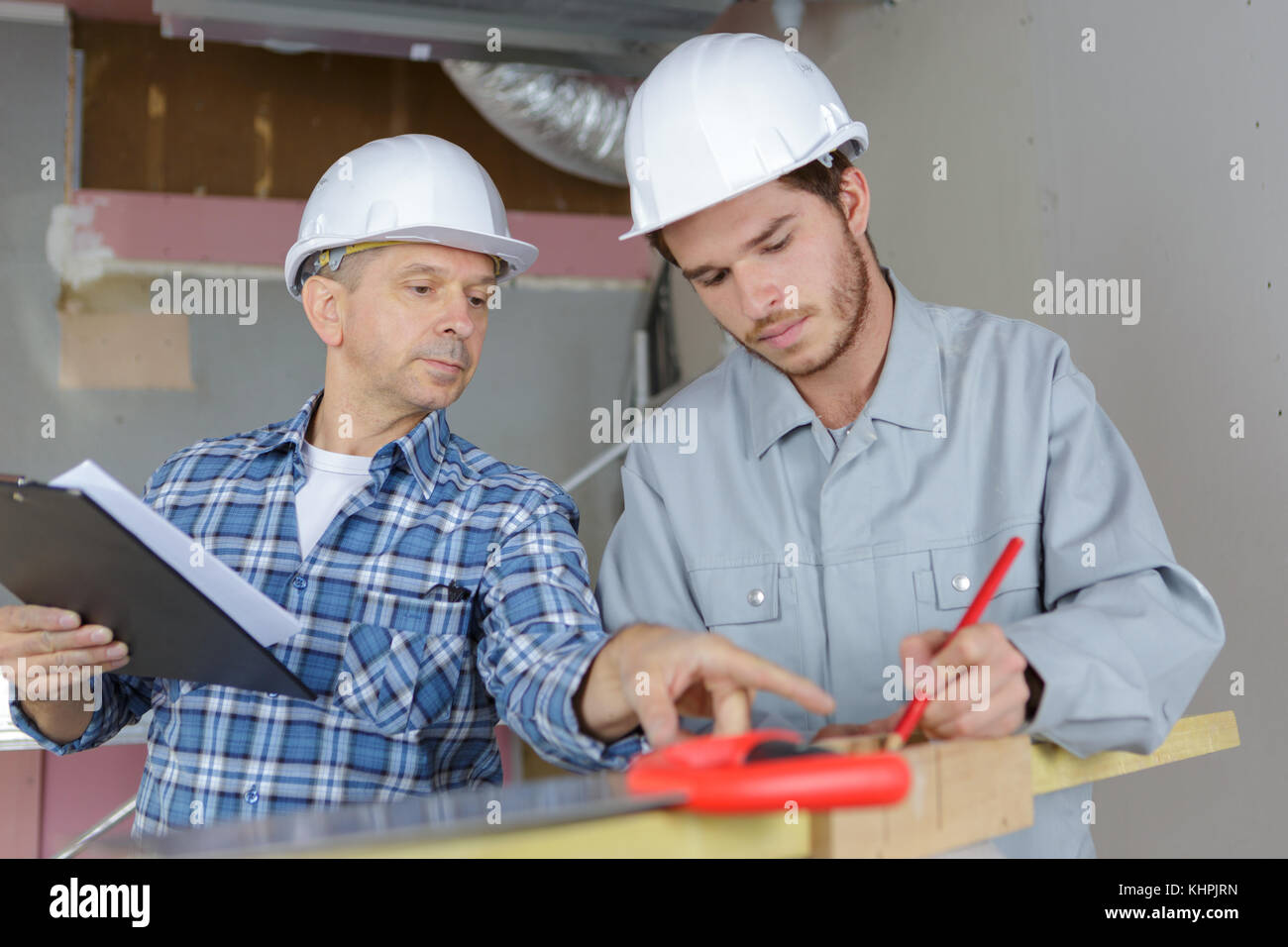 builder showing apprentice where to cut Stock Photo - Alamy