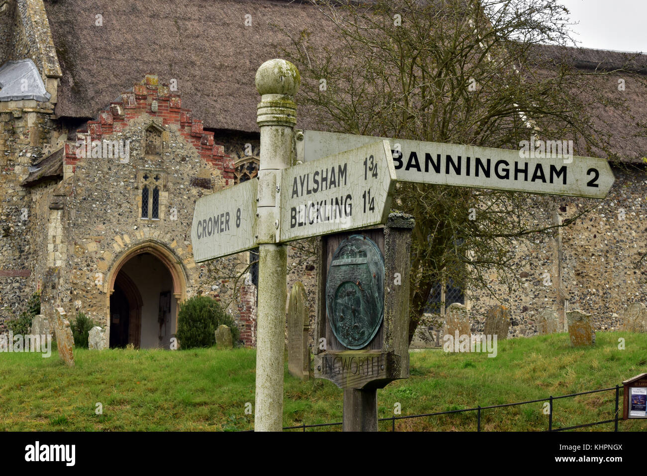 A Norfolk village signpost in front of an historic church giving ...