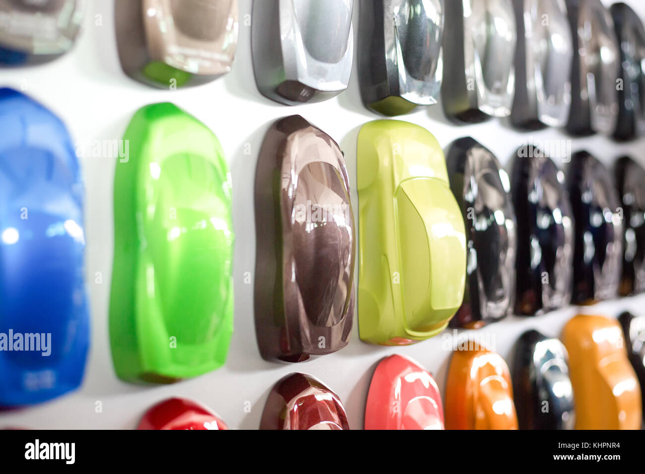 Small plastic colored cars attached to the white wall placed in three ...