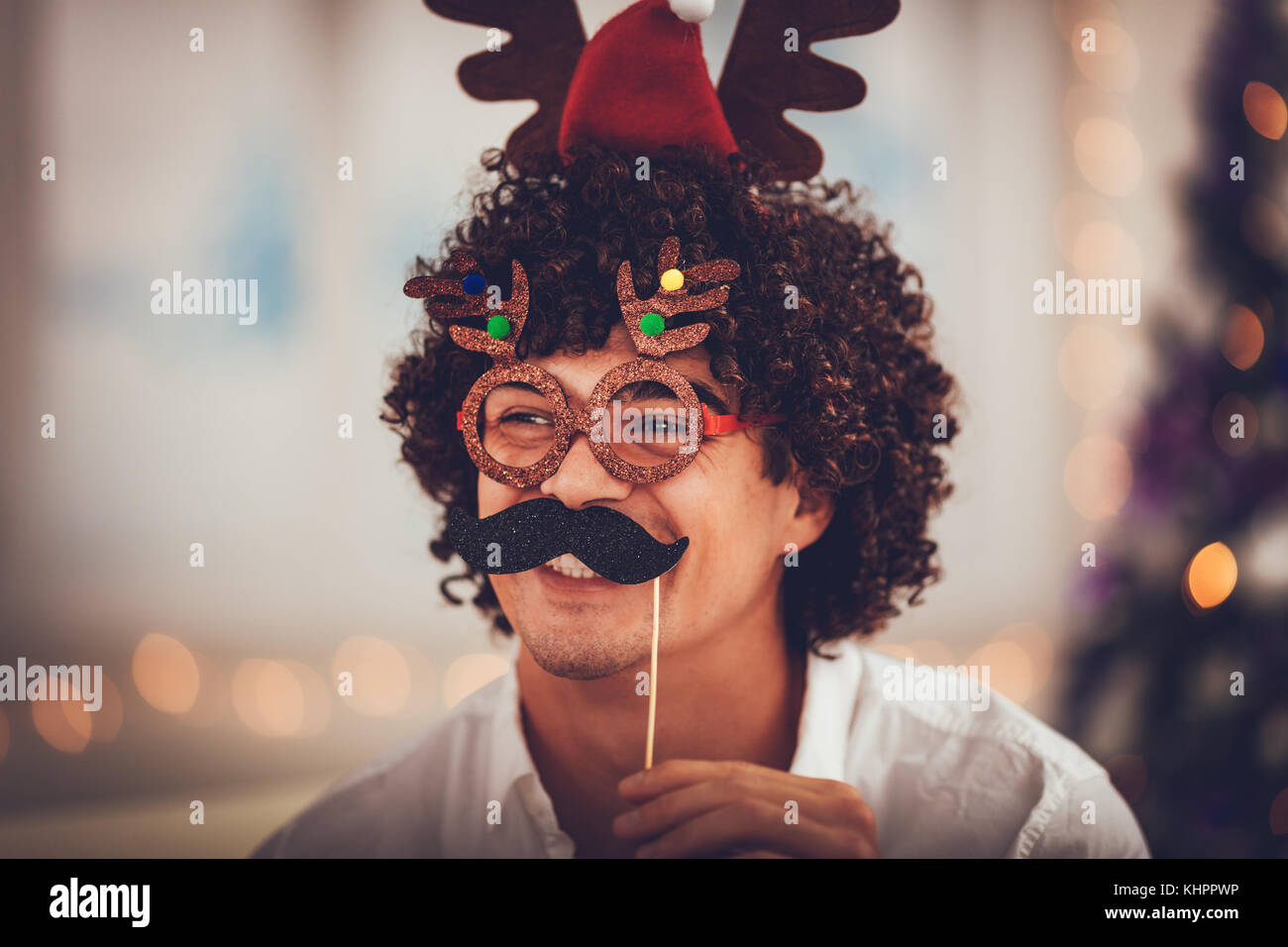 Portrait of a handsome young smiling man with funny christmas masks ...