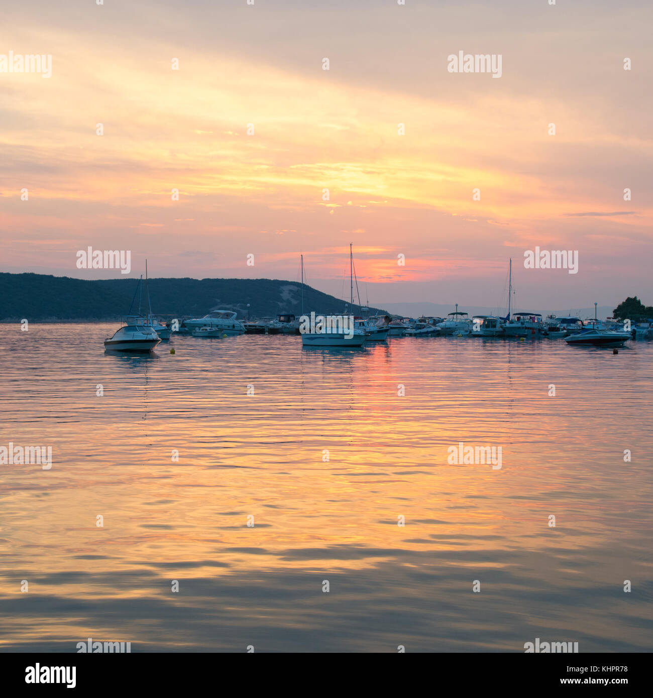 The fiery sunset reflects on the sea of a small marina Stock Photo - Alamy