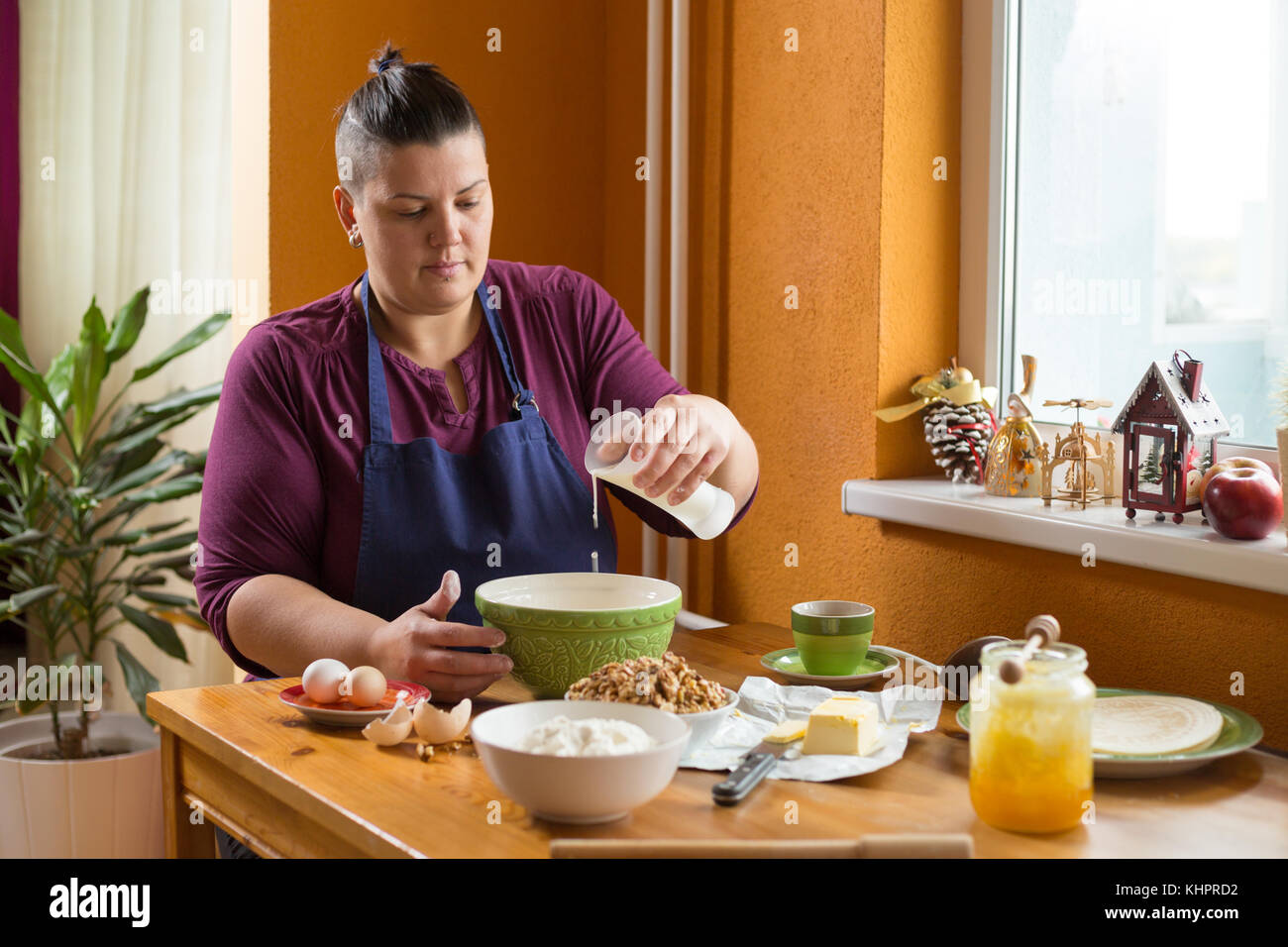 Young european woman sitting in the kitchen behind a wooden kitchen ...