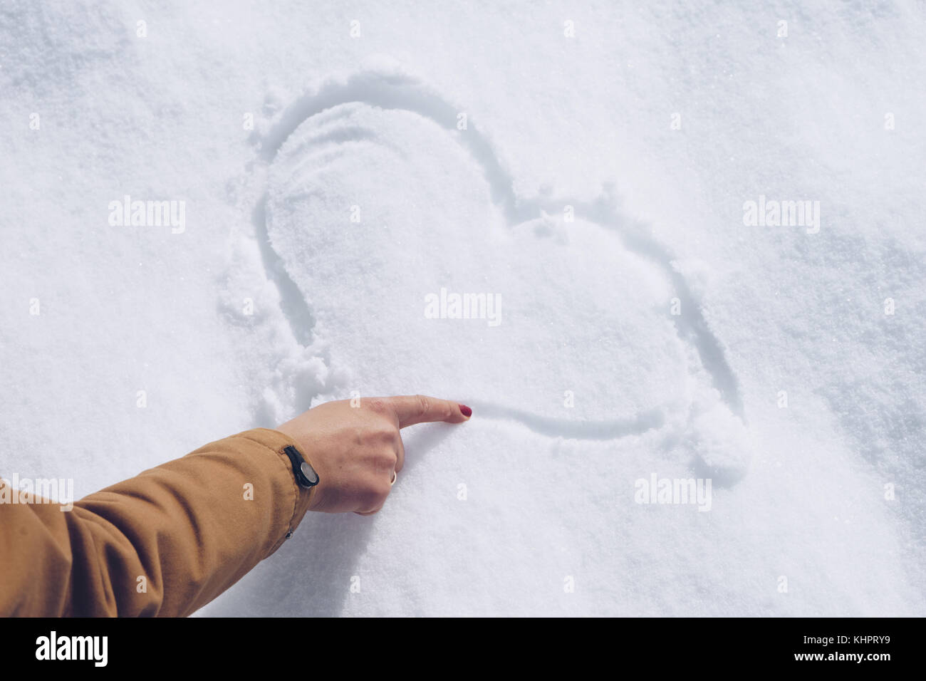 Woman is drawing a heart on the snow Stock Photo - Alamy