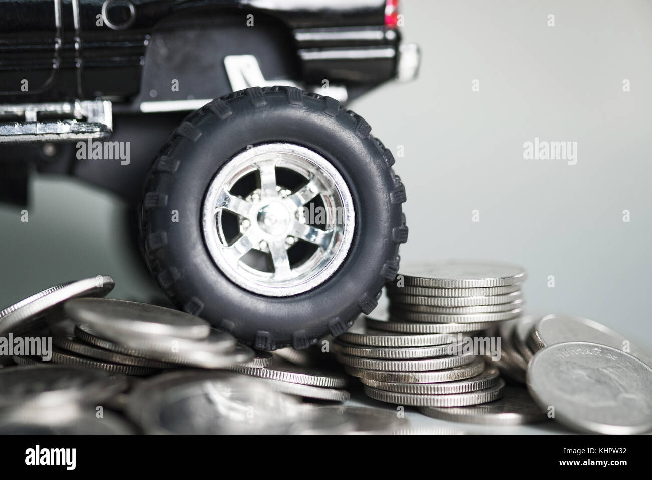 Close up of tire of miniature car pickup truck on stacks of coins with ...