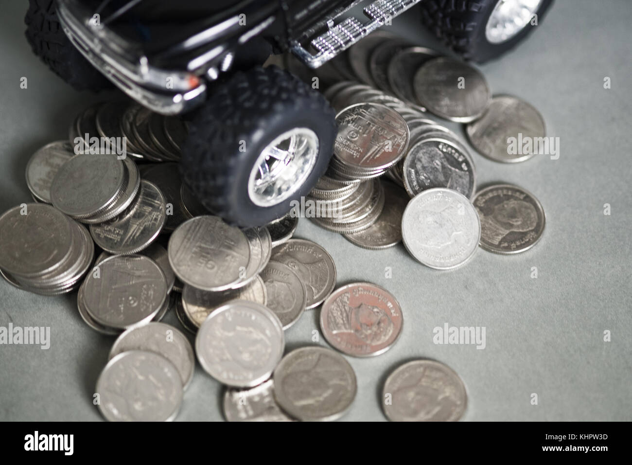 Close up of tire of miniature car pickup truck on stacks of coins with ...