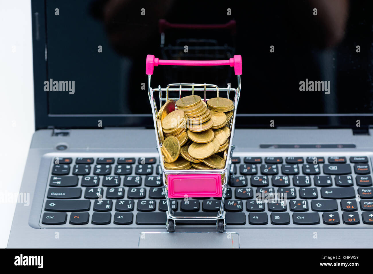Stack of coins in shopping cart or supermarket trolley with laptop ...