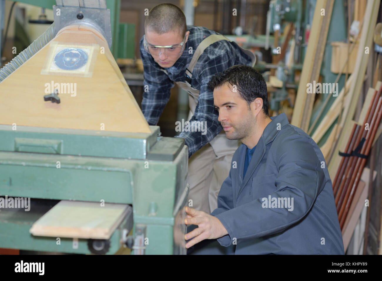 carpenter training male apprentice to use mechanized saw Stock Photo ...
