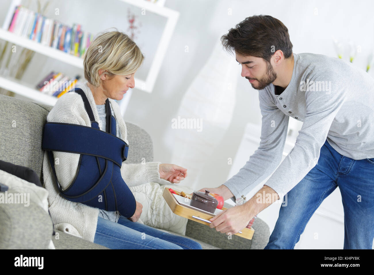 young helpful man spending time with injured lady Stock Photo - Alamy