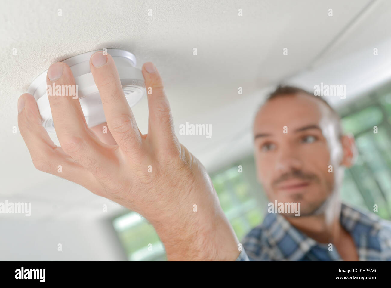 Man with his hand on a smoke detector Stock Photo - Alamy