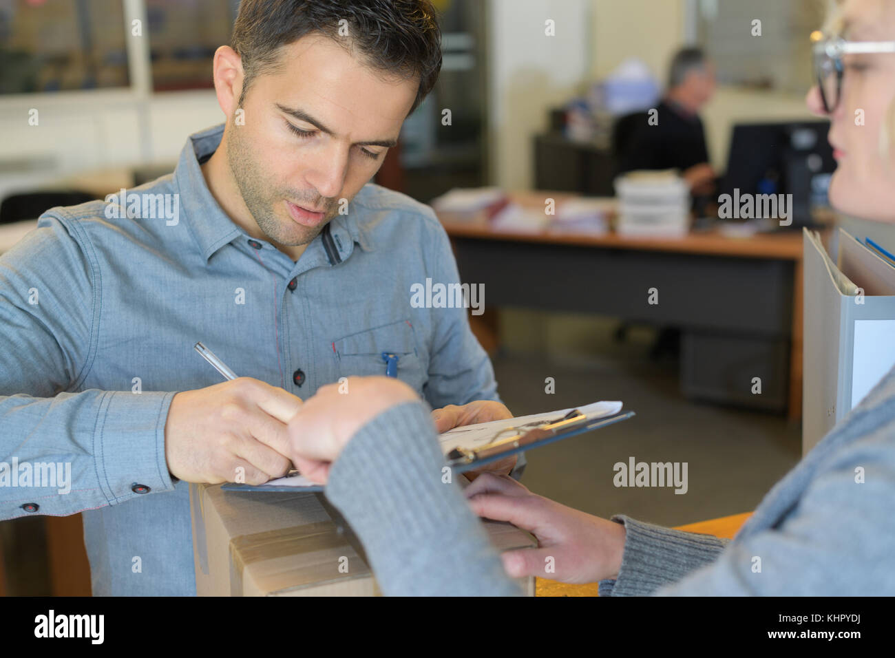 man signing for the delivery of boxes Stock Photo - Alamy