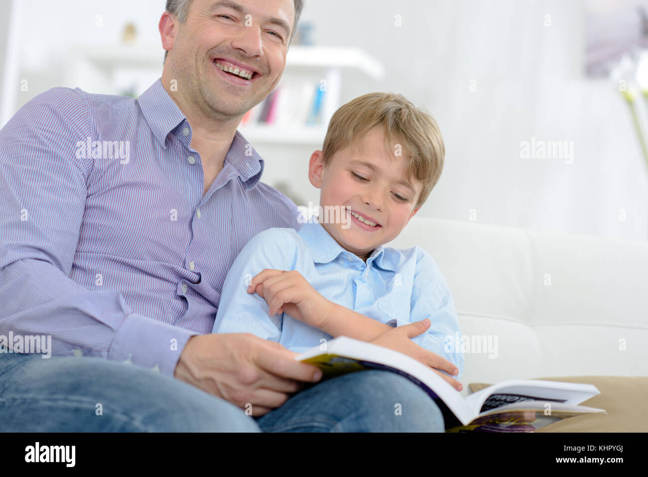 Father and son laughing while reading book Stock Photo - Alamy