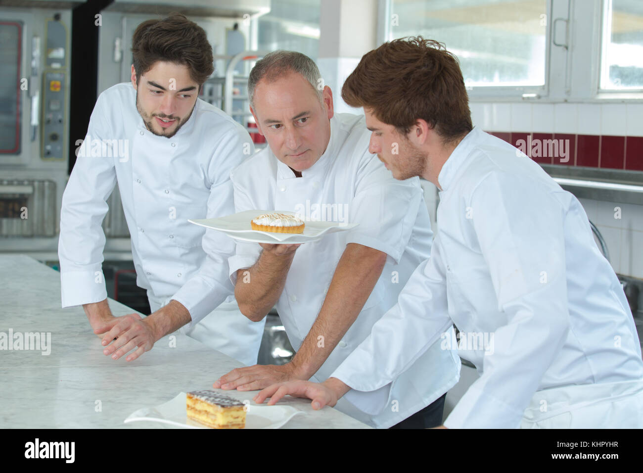 Senior chef showing cake to trainees Stock Photo - Alamy