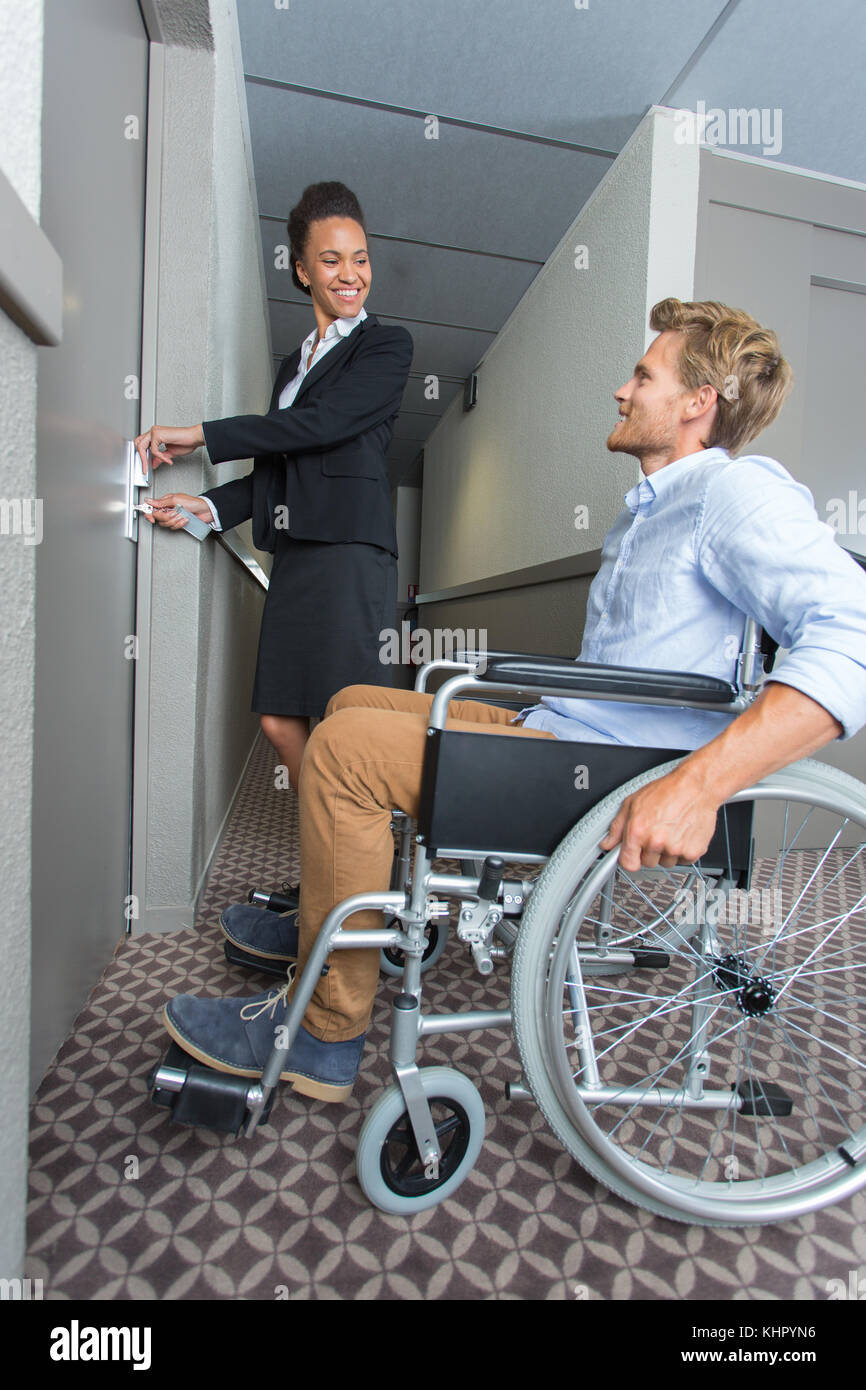 hotel assistant taken care of a young man in wheelchair Stock Photo - Alamy