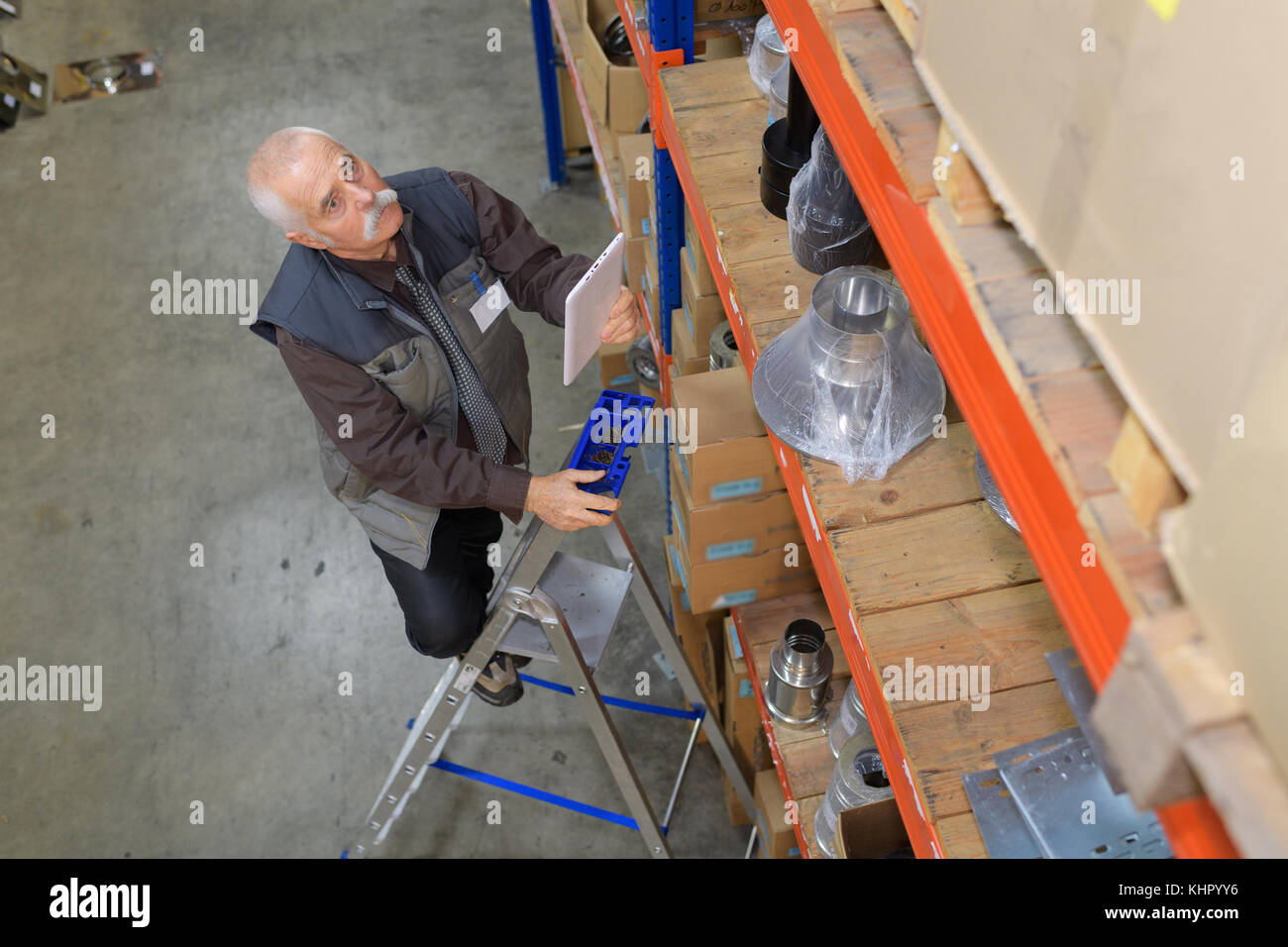 Senior man on step ladder looking up into racking Stock Photo - Alamy