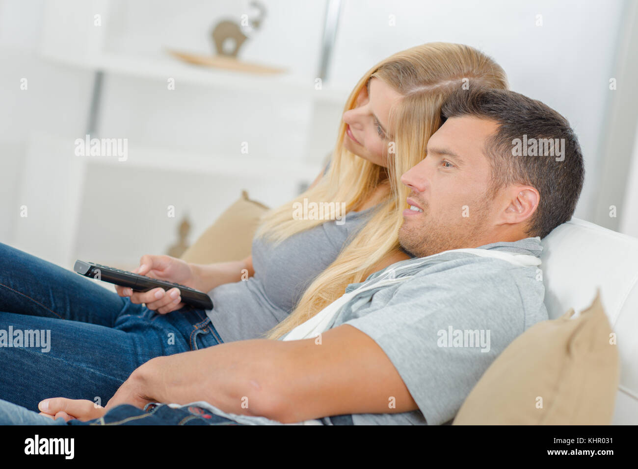 Side view of couple on couch watching TV Stock Photo - Alamy