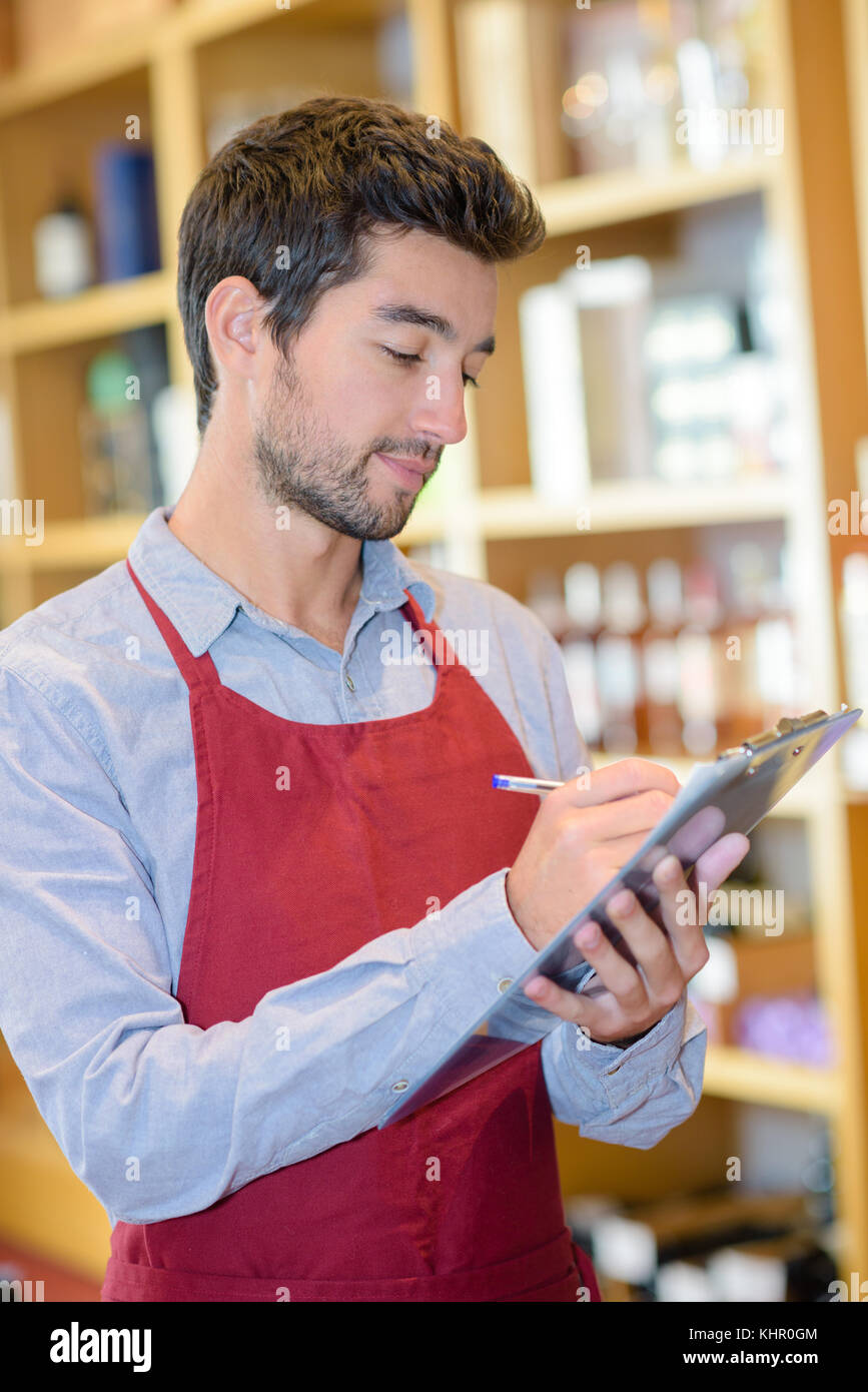 male vendor with apron on writing on the clipboard Stock Photo - Alamy