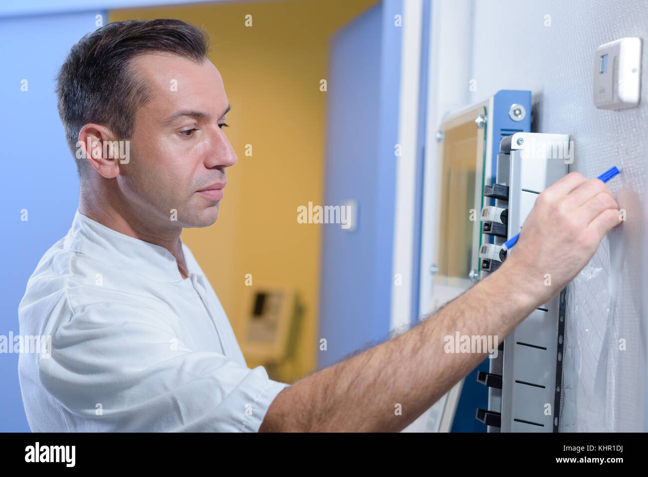 Man in white coat at clocking in machine Stock Photo - Alamy