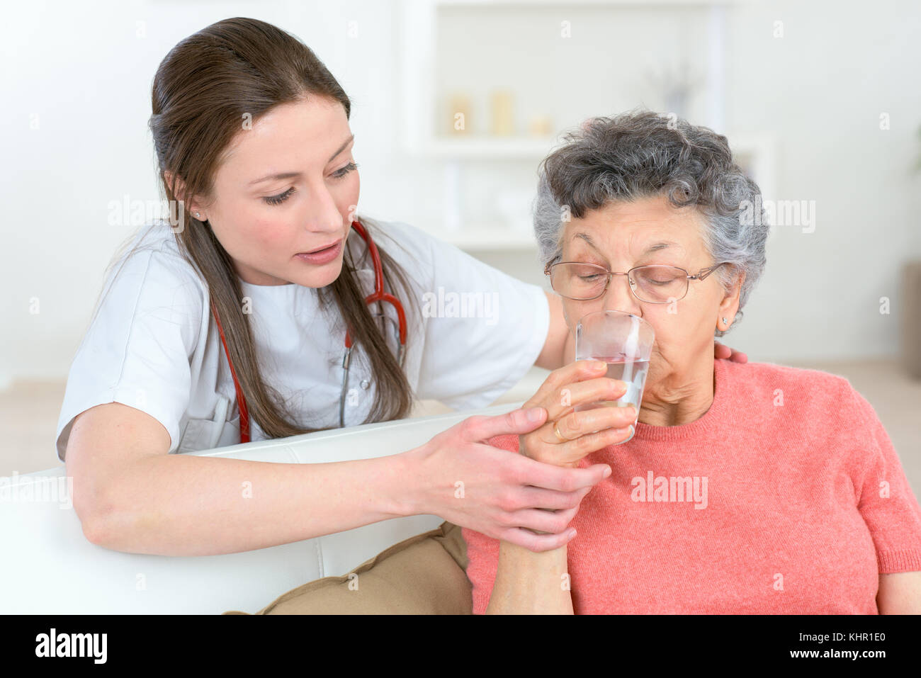 doctor giving sick senior woman a glass of water Stock Photo - Alamy