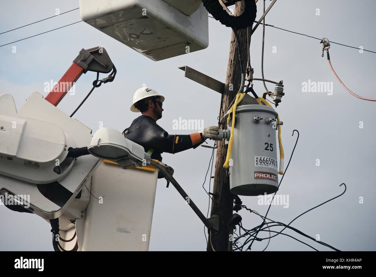 A utility worker repairs a damaged electrical transformer to restore ...