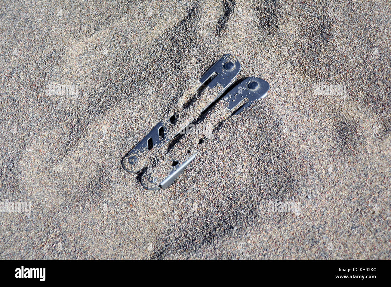 A stainless steel multi-tool dropped in the sand Stock Photo - Alamy
