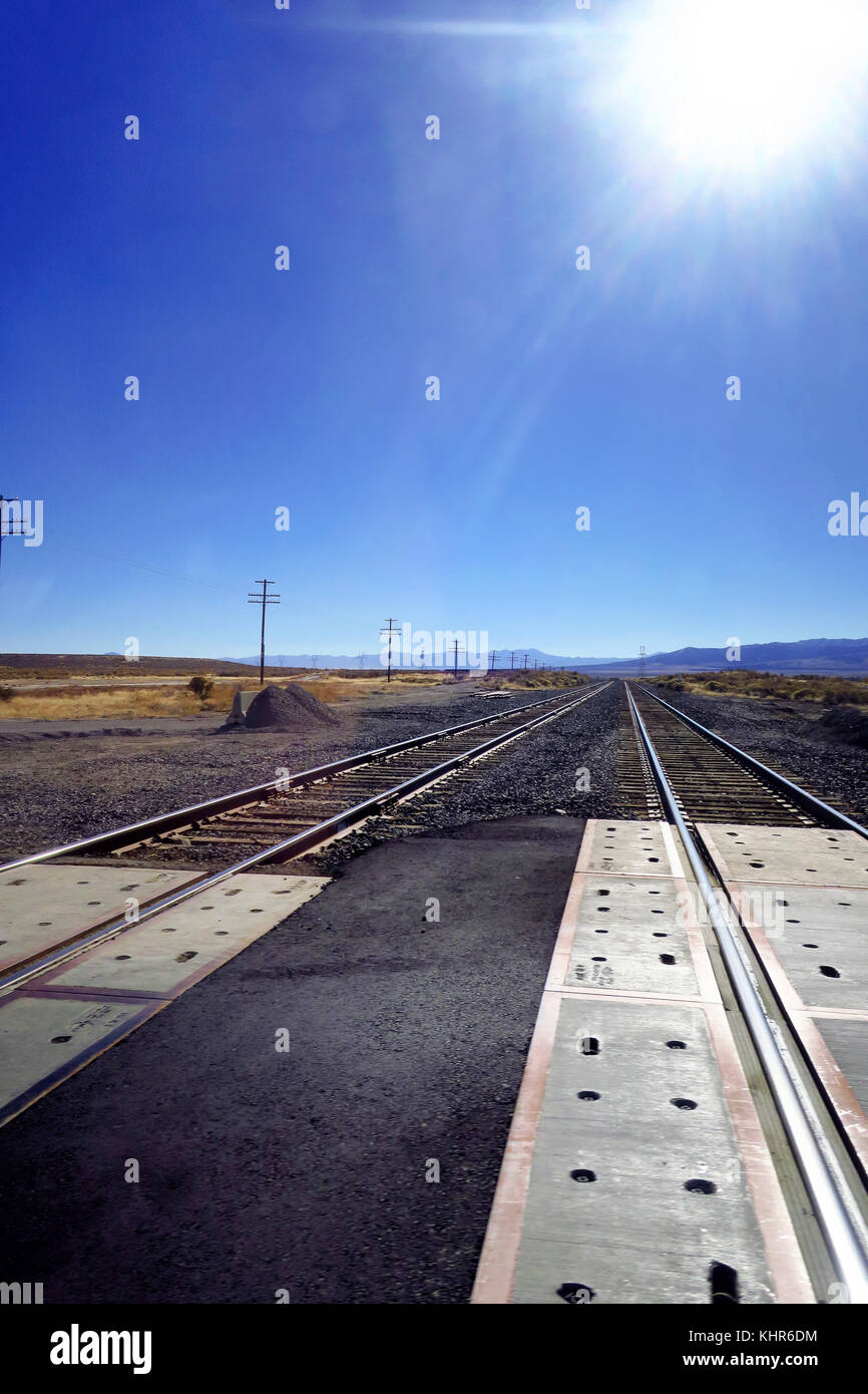 Two railroad tracks at a crossing light up by solar flare on a bright ...