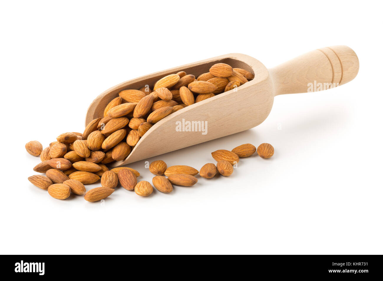 Heap of shelled almond kernels in wooden scoop over white background ...