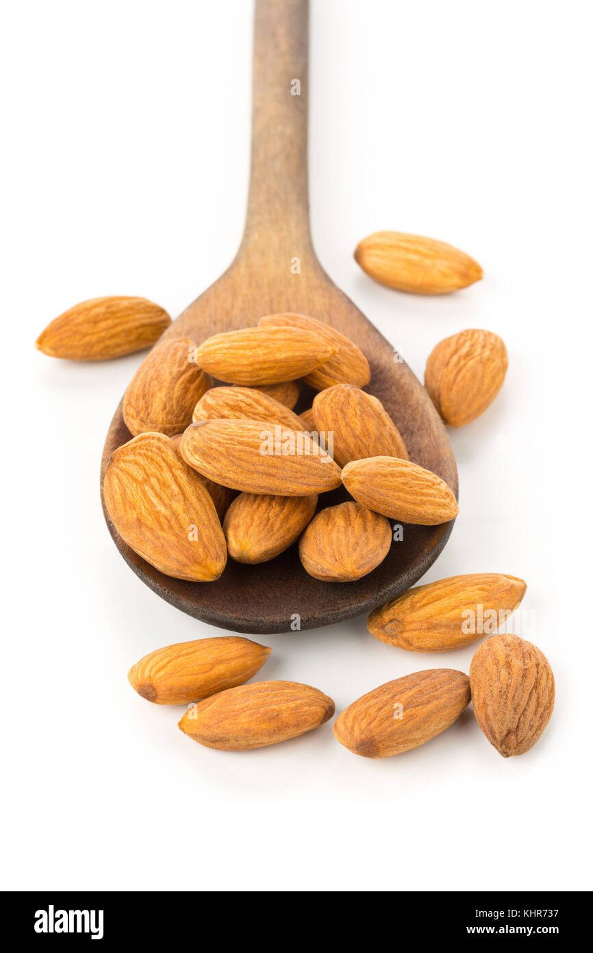 Heap of shelled almond kernels in wooden spoon over white background ...