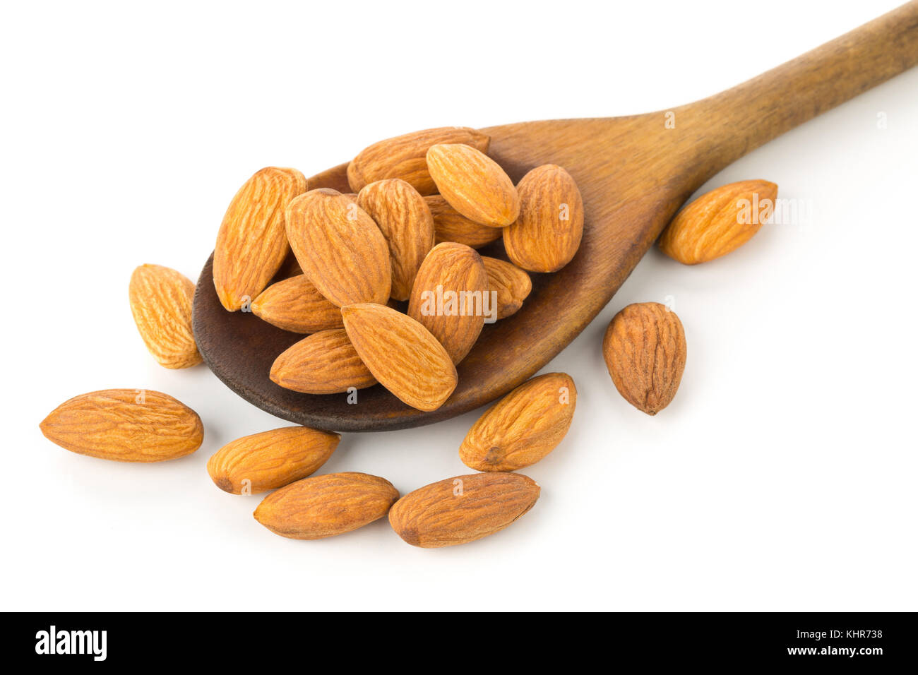 Heap of shelled almond kernels in wooden spoon over white background ...