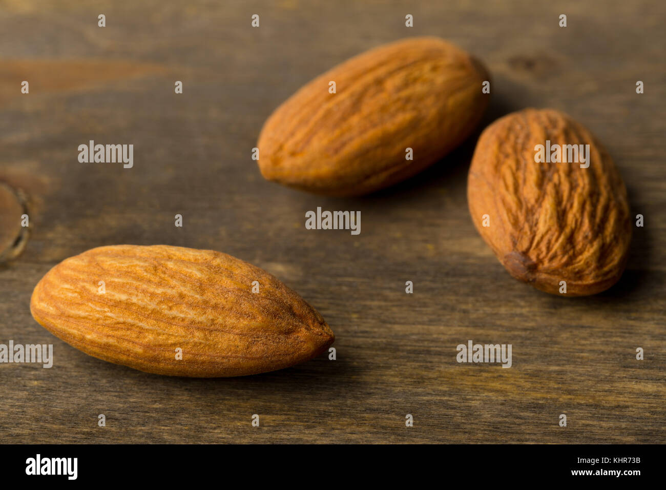 Macro of shelled almond kernels with selective focus on wood background ...