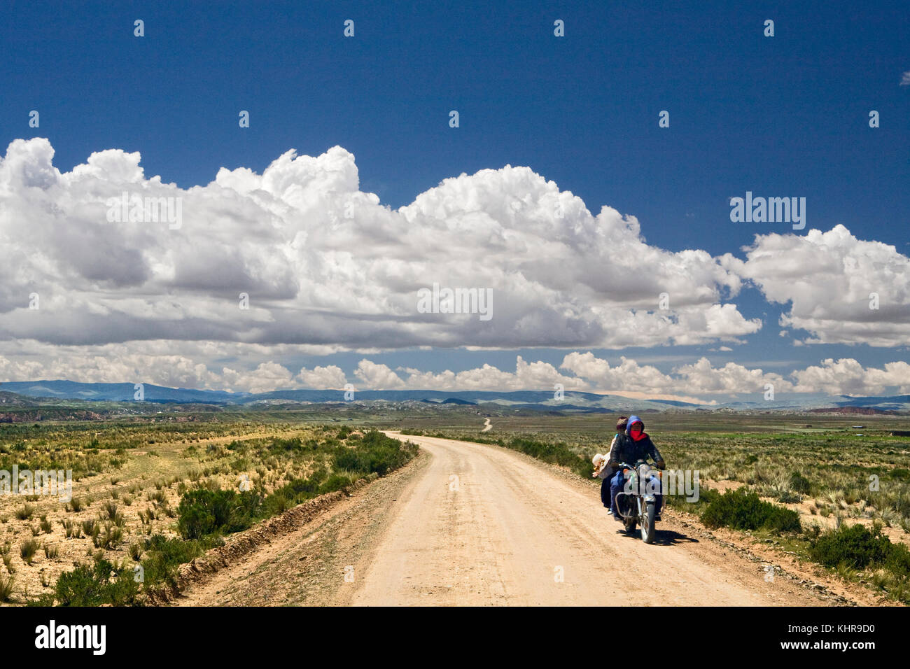 Man and woman riding motorcycle through dry puna, Andes, western ...