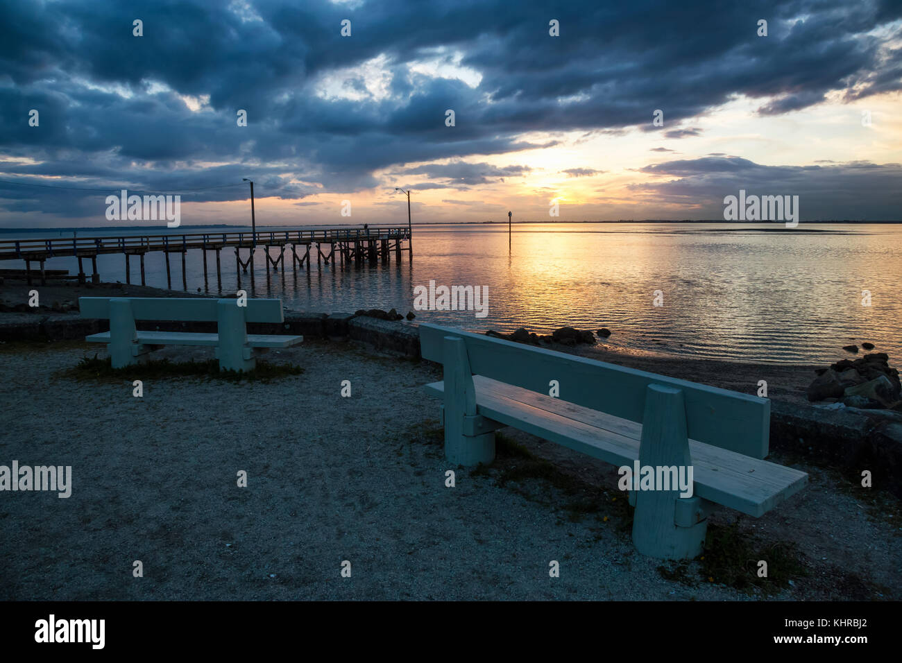 Benches in front of a beautiful sunset at the beach by the wooden quay ...