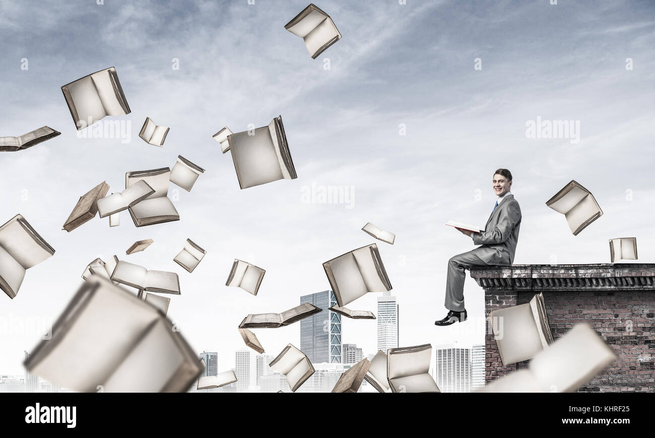 Man on roof reading book and many of them flying in air Stock Photo - Alamy